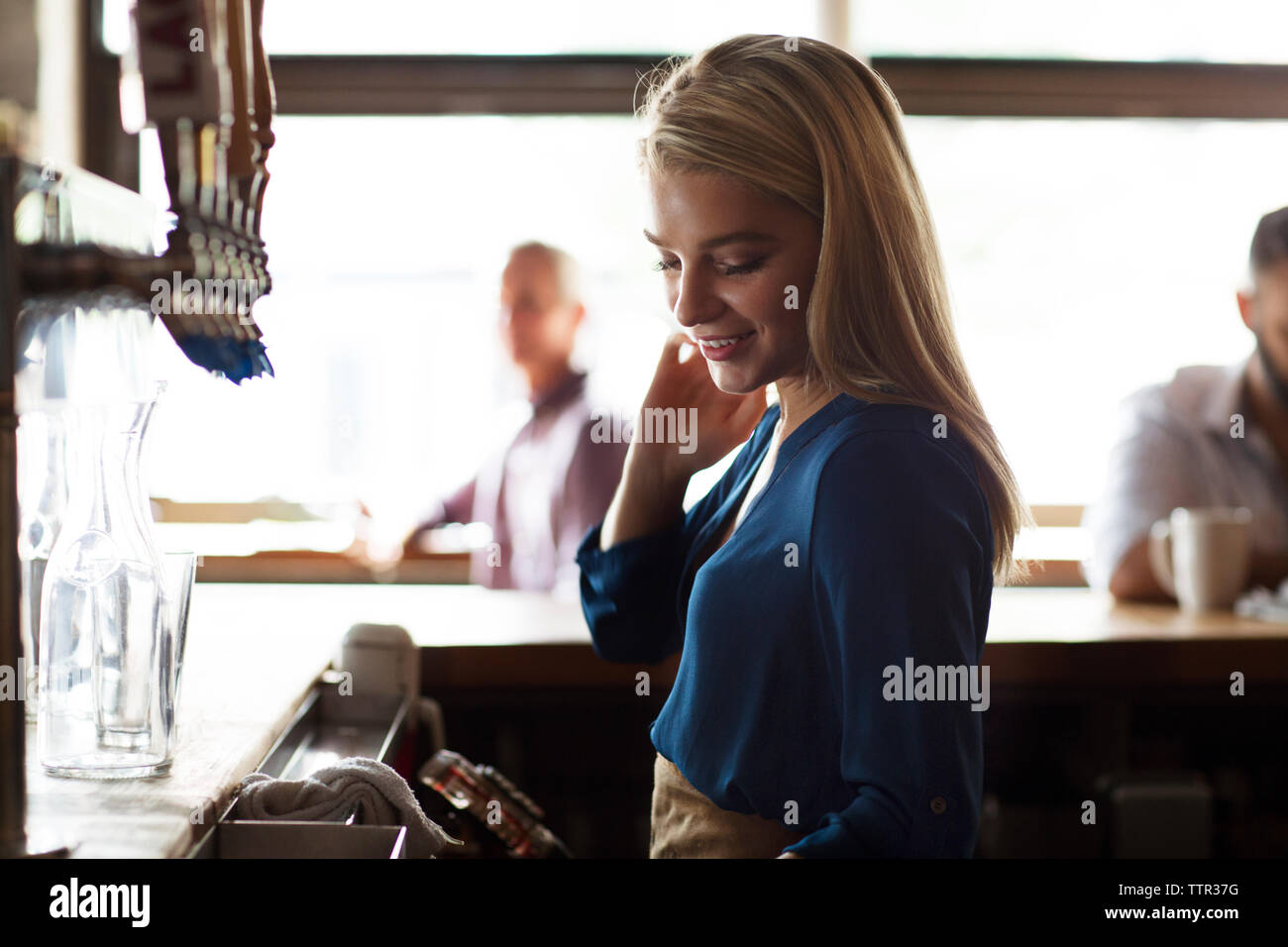 Smiling female owner standing at bar counter in cafe Stock Photo - Alamy