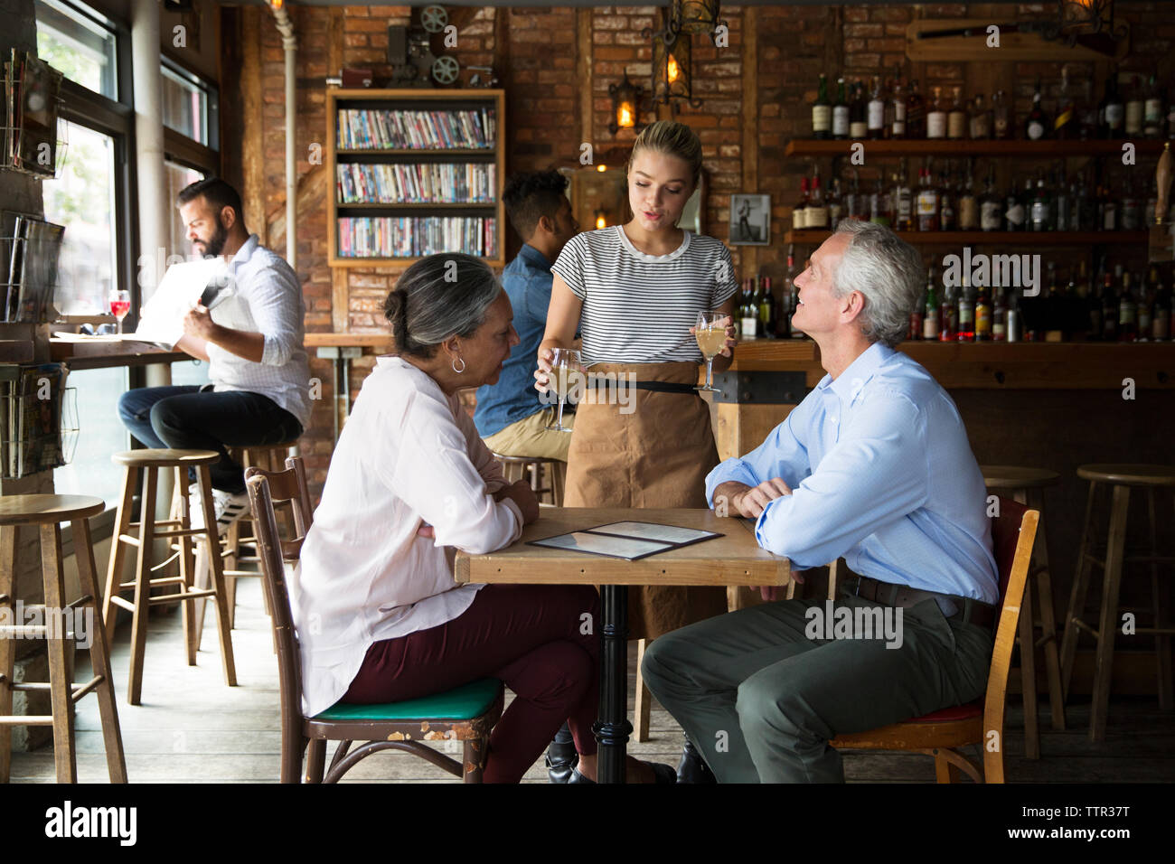 Waitress serving drinks to customers at cafe Stock Photo - Alamy