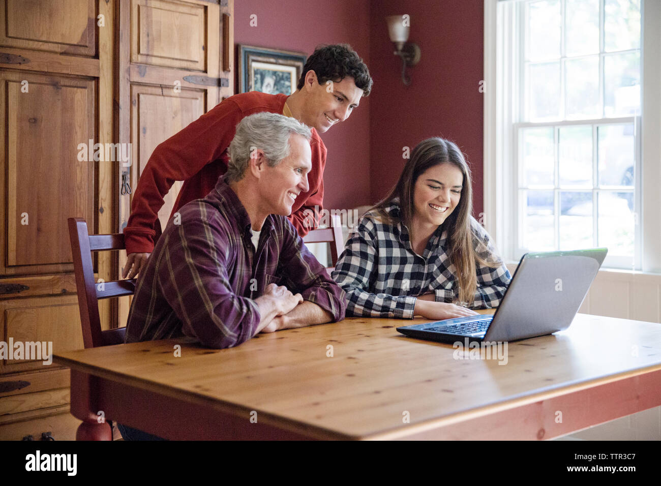 Family looking at laptop computer at home Stock Photo - Alamy