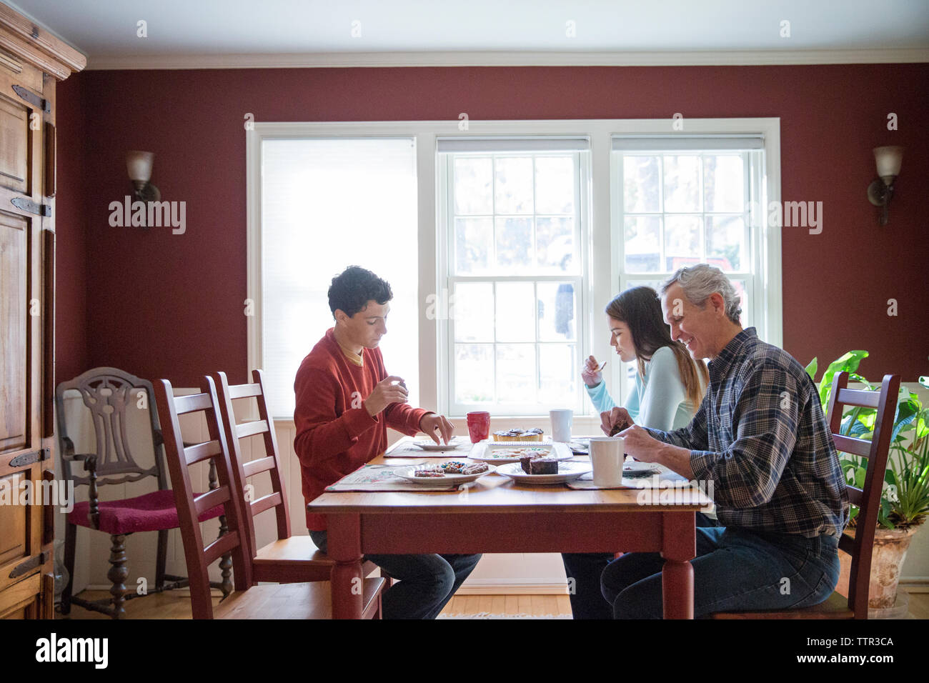 Happy family eating breakfast at table in home Stock Photo - Alamy