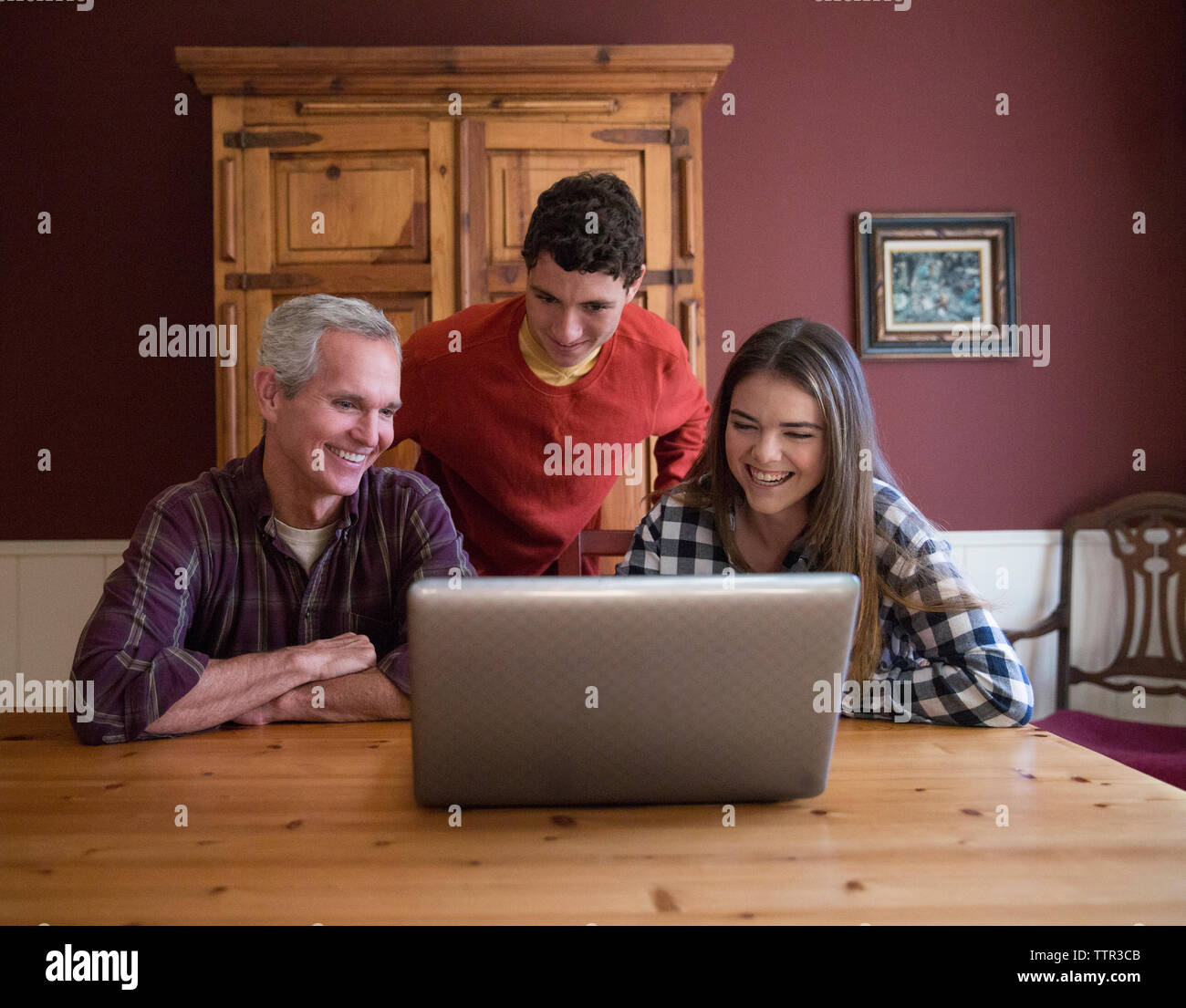 Happy family using laptop computer at table in home Stock Photo - Alamy