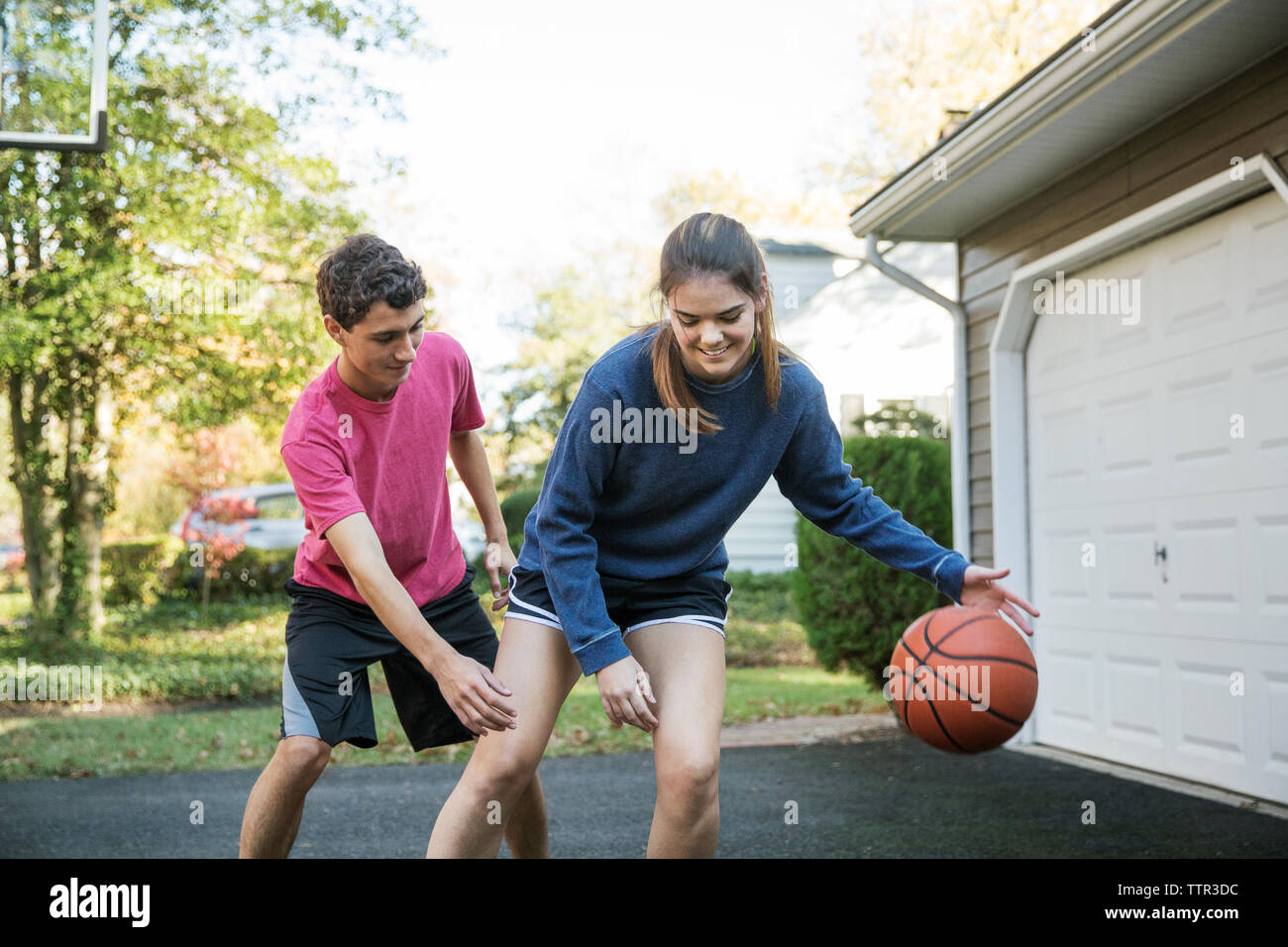Happy brother and sister playing basketball at backyard Stock Photo - Alamy