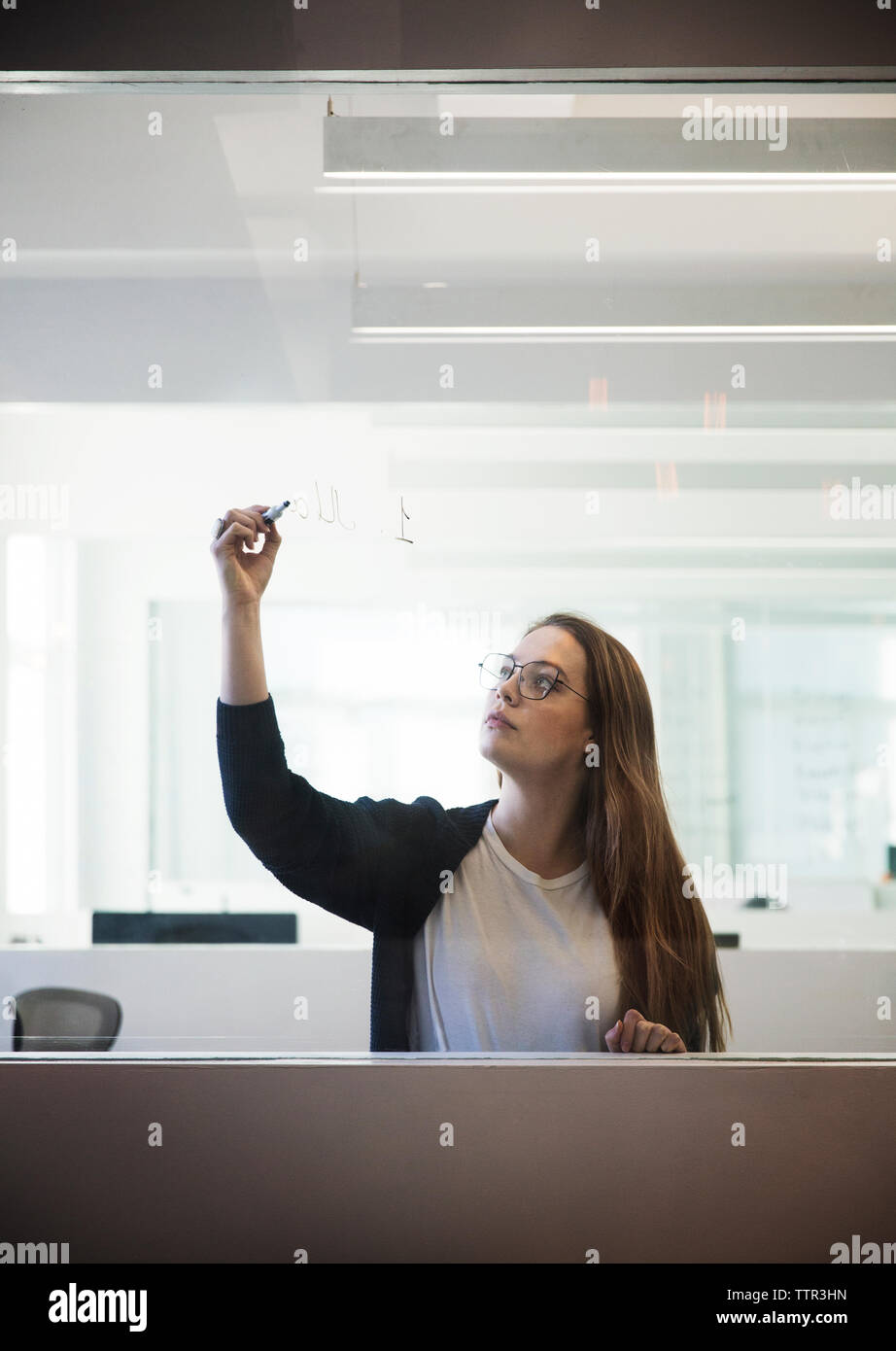 Woman writing on window in office Stock Photo - Alamy