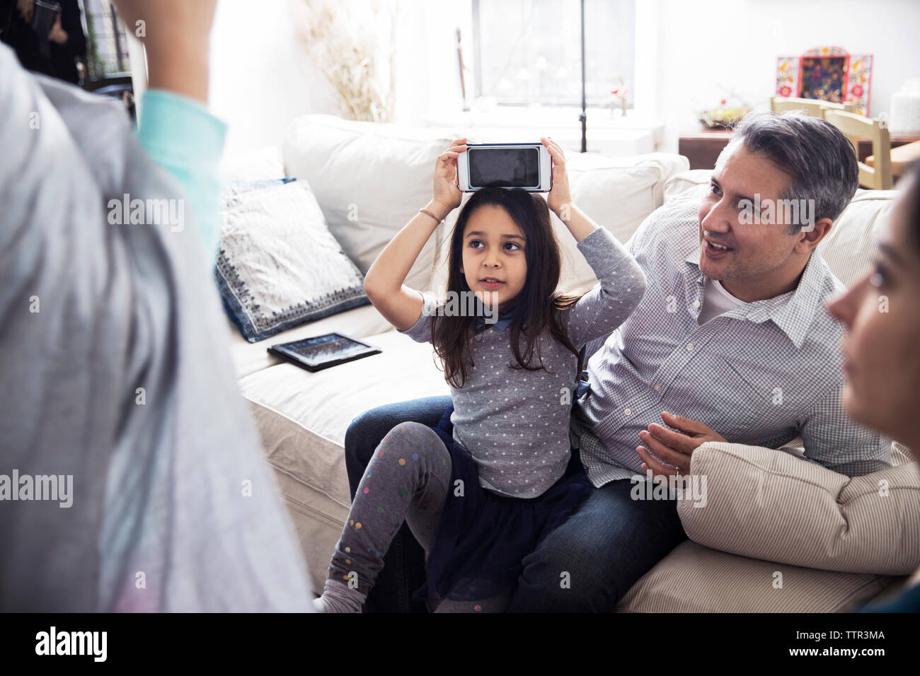 Parents looking at girls playing heads up game Stock Photo - Alamy