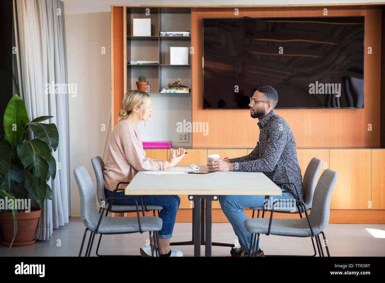 Side view of colleagues planning at table in office Stock Photo - Alamy