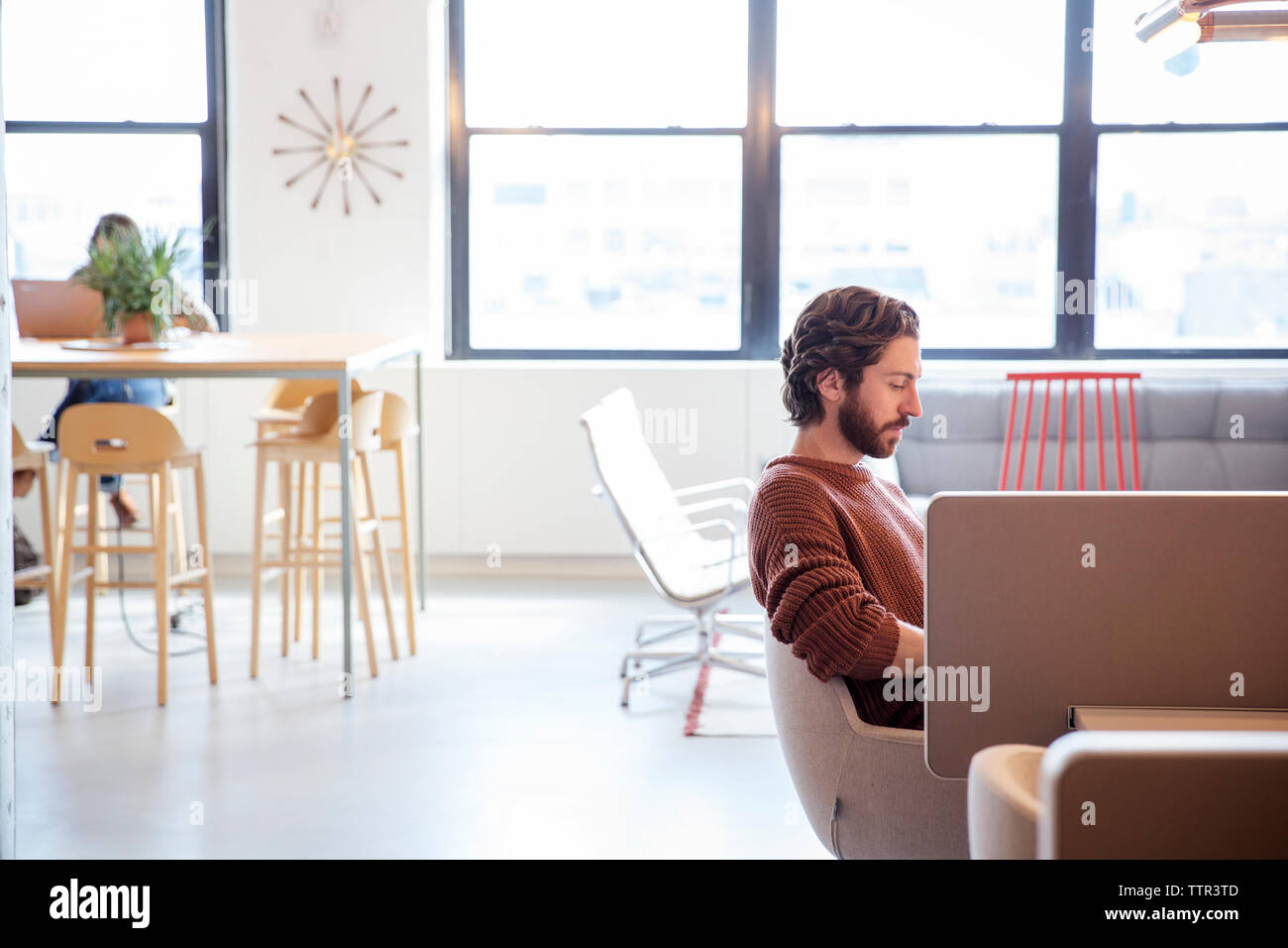 Side view of businessman sitting on chair in office Stock Photo - Alamy