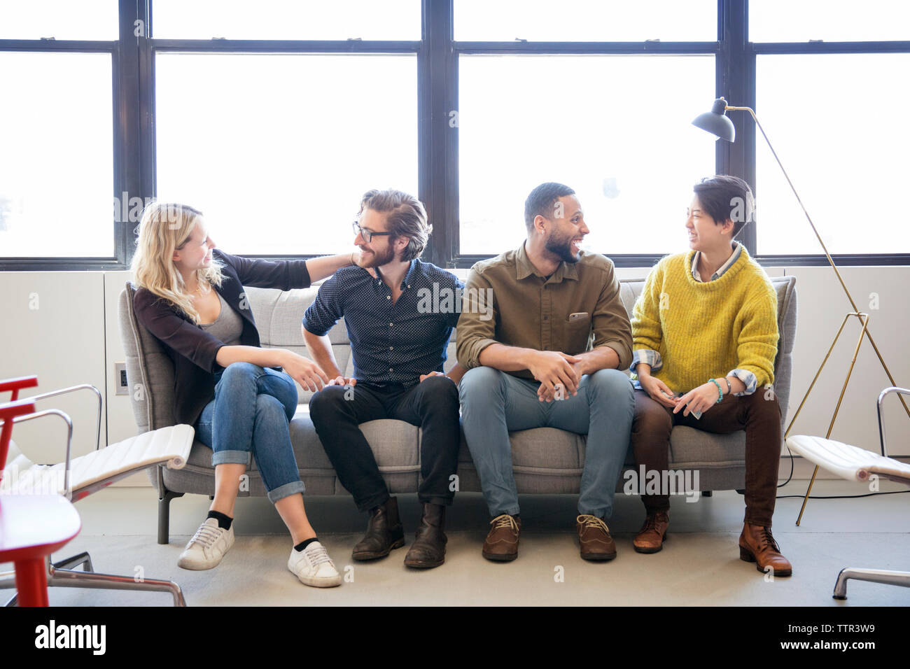 Happy business people talking while sitting on sofa in office Stock ...