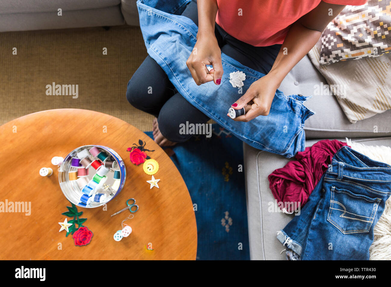 High angle view of woman removing thread from spool while sitting on ...