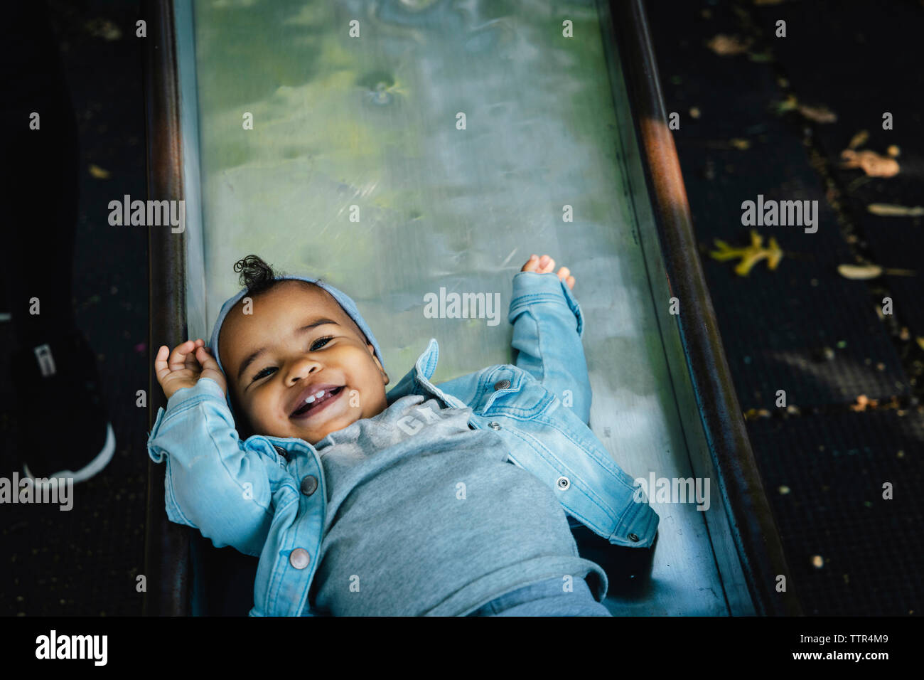 High angle portrait of happy cute baby girl sliding at playground Stock ...