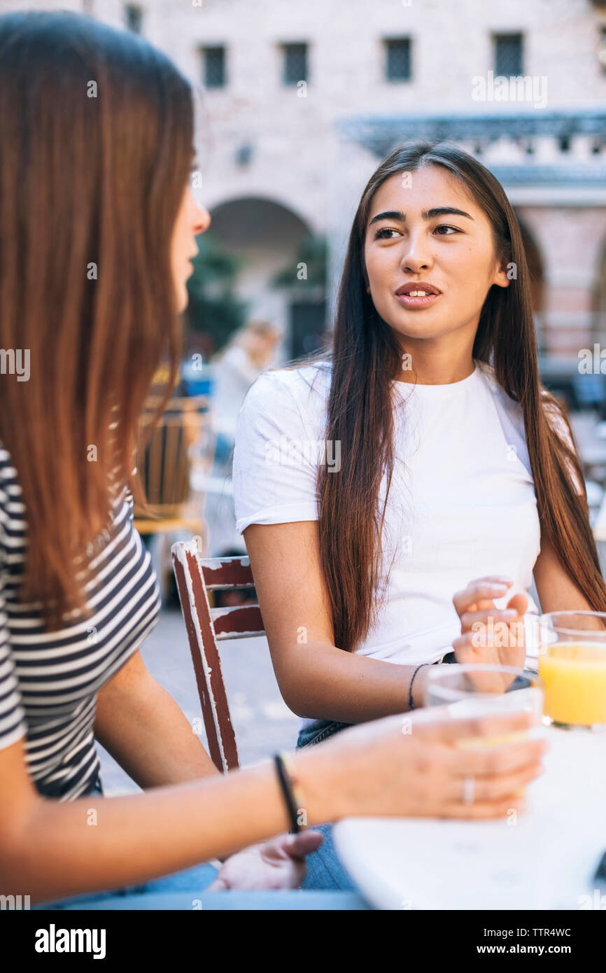 Friends talking while sitting by table at sidewalk cafe Stock Photo - Alamy
