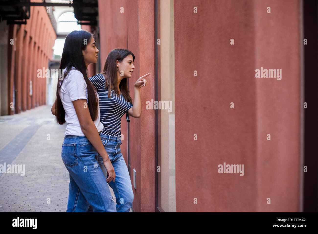 Woman showing direction to female friend while standing at alley in ...