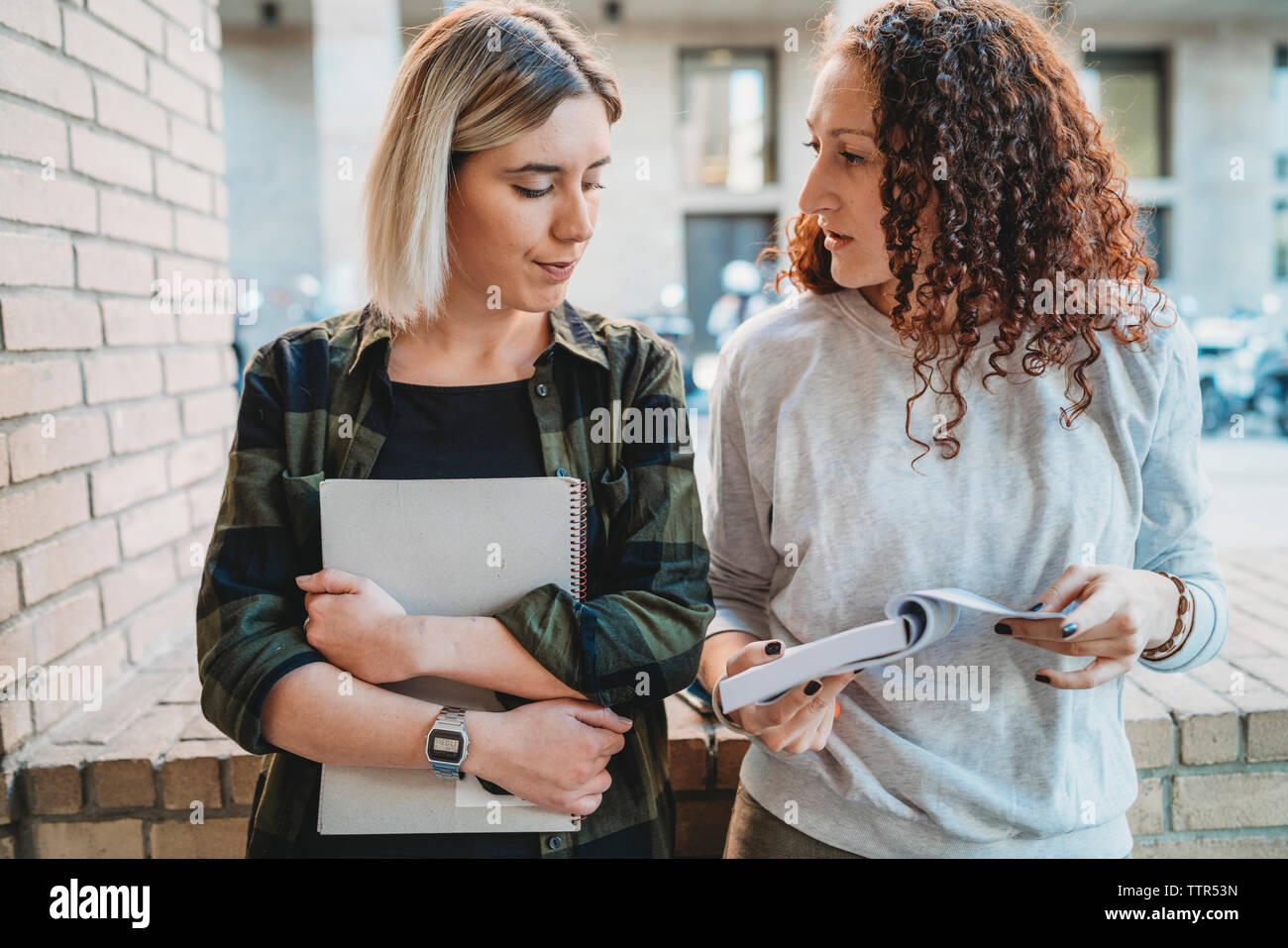 Two young students talking together in the college Stock Photo - Alamy