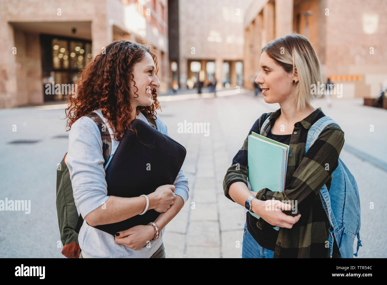 Two young students talking together in the college Stock Photo - Alamy