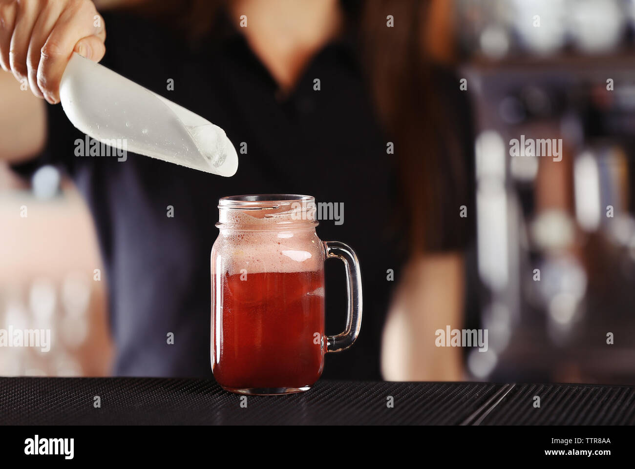 Woman hands adding ice into cocktail on bar counter Stock Photo - Alamy