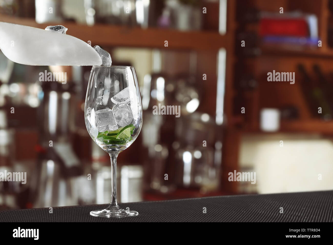 Woman hands adding ice into cocktail on bar counter Stock Photo - Alamy