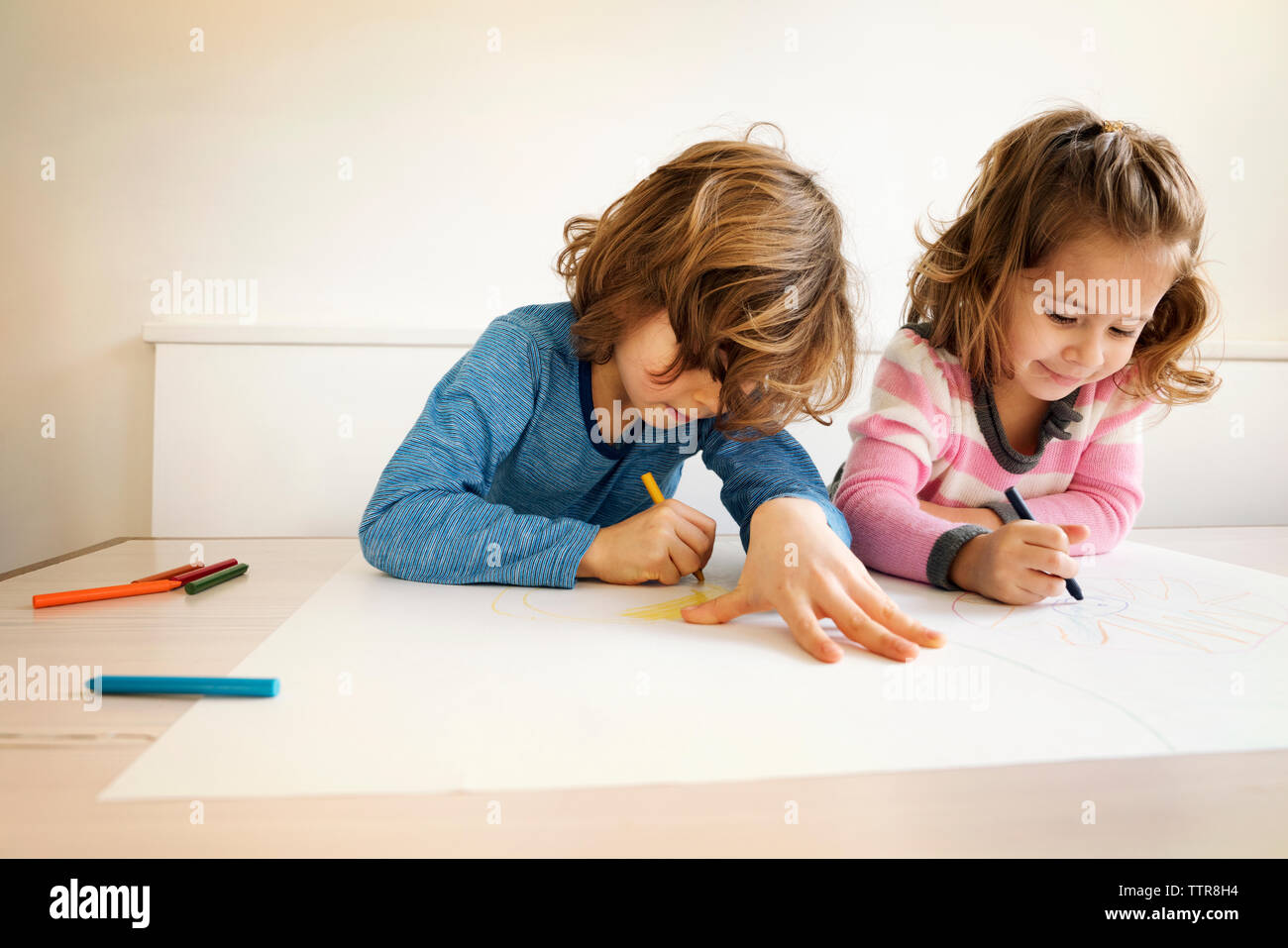 Siblings drawing at table in home Stock Photo - Alamy