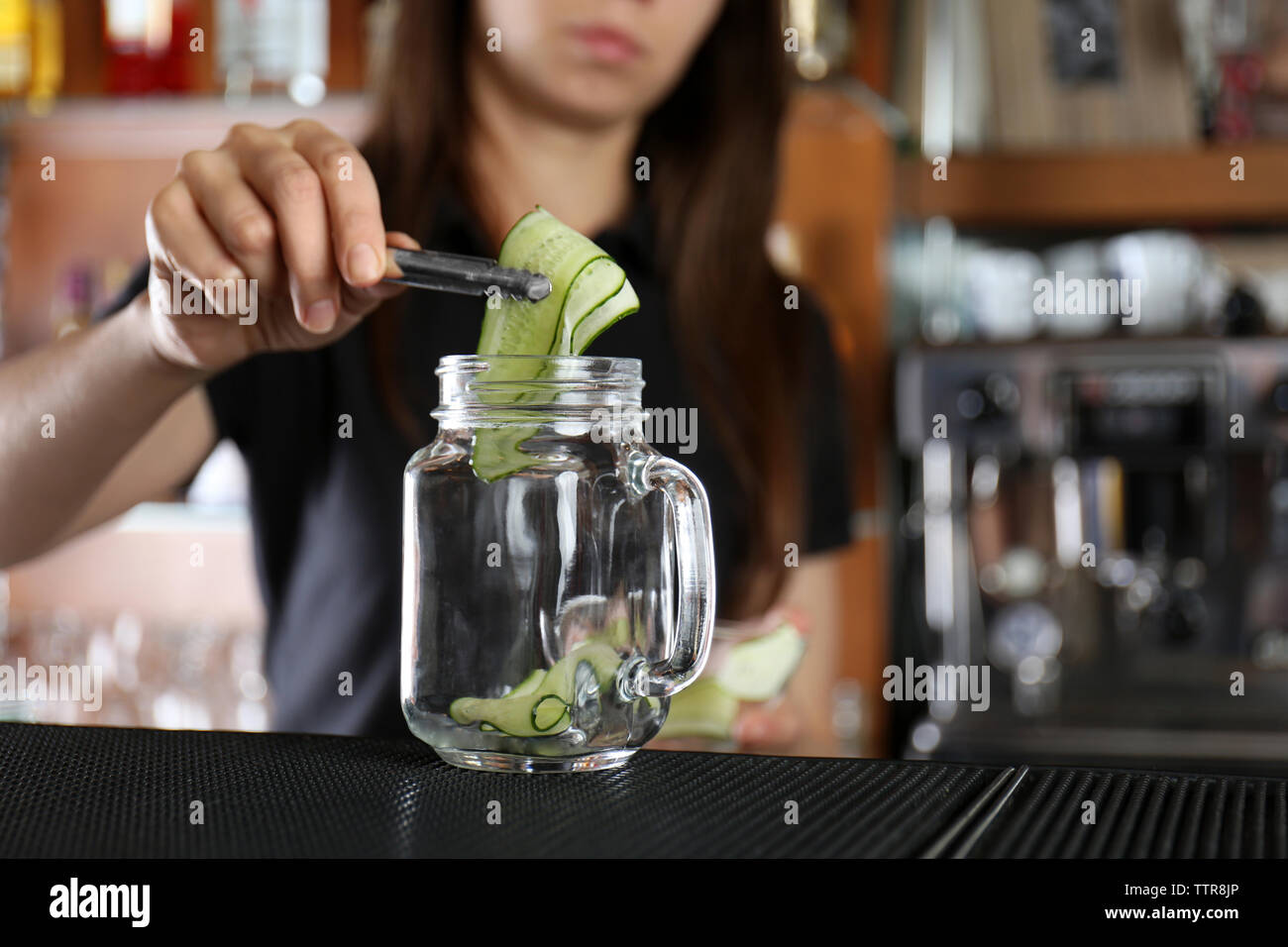 Woman hands putting cucumber into glass jar on bar counter Stock Photo ...