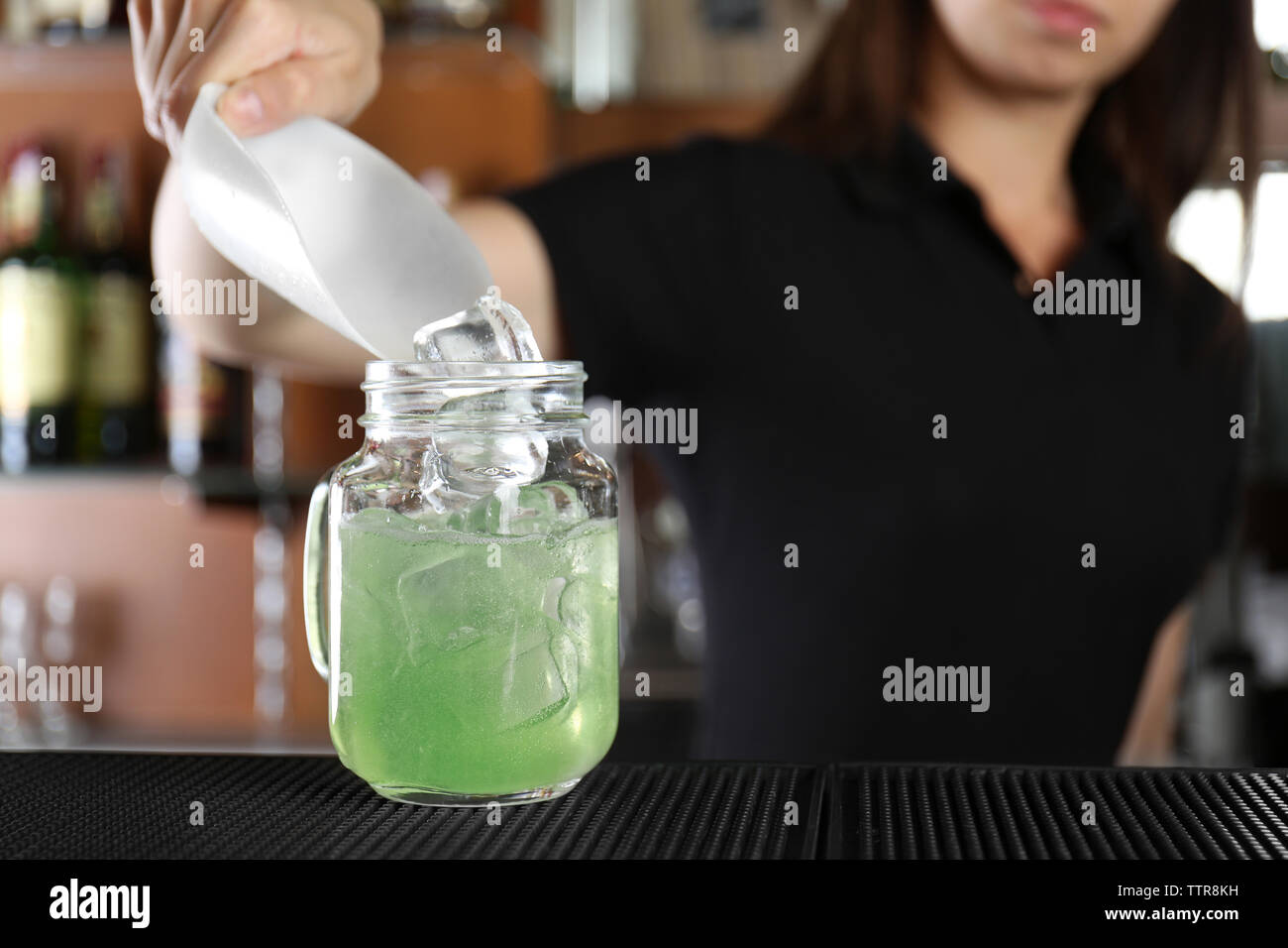 Woman hands adding ice into cocktail on bar counter Stock Photo - Alamy