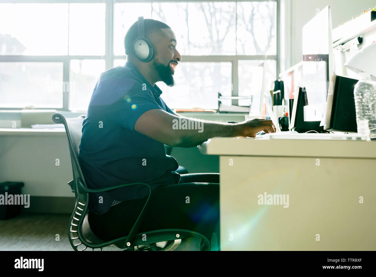 Side view of smiling businessman using desktop computer while working ...