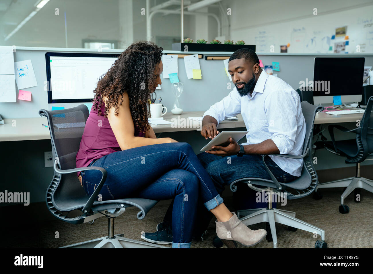 business people discussing over tablet computer while sitting at desk ...