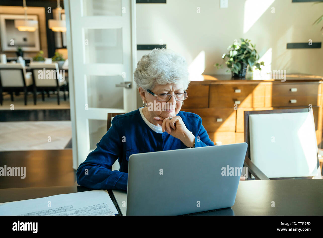 Serious senior woman using laptop computer at home Stock Photo - Alamy