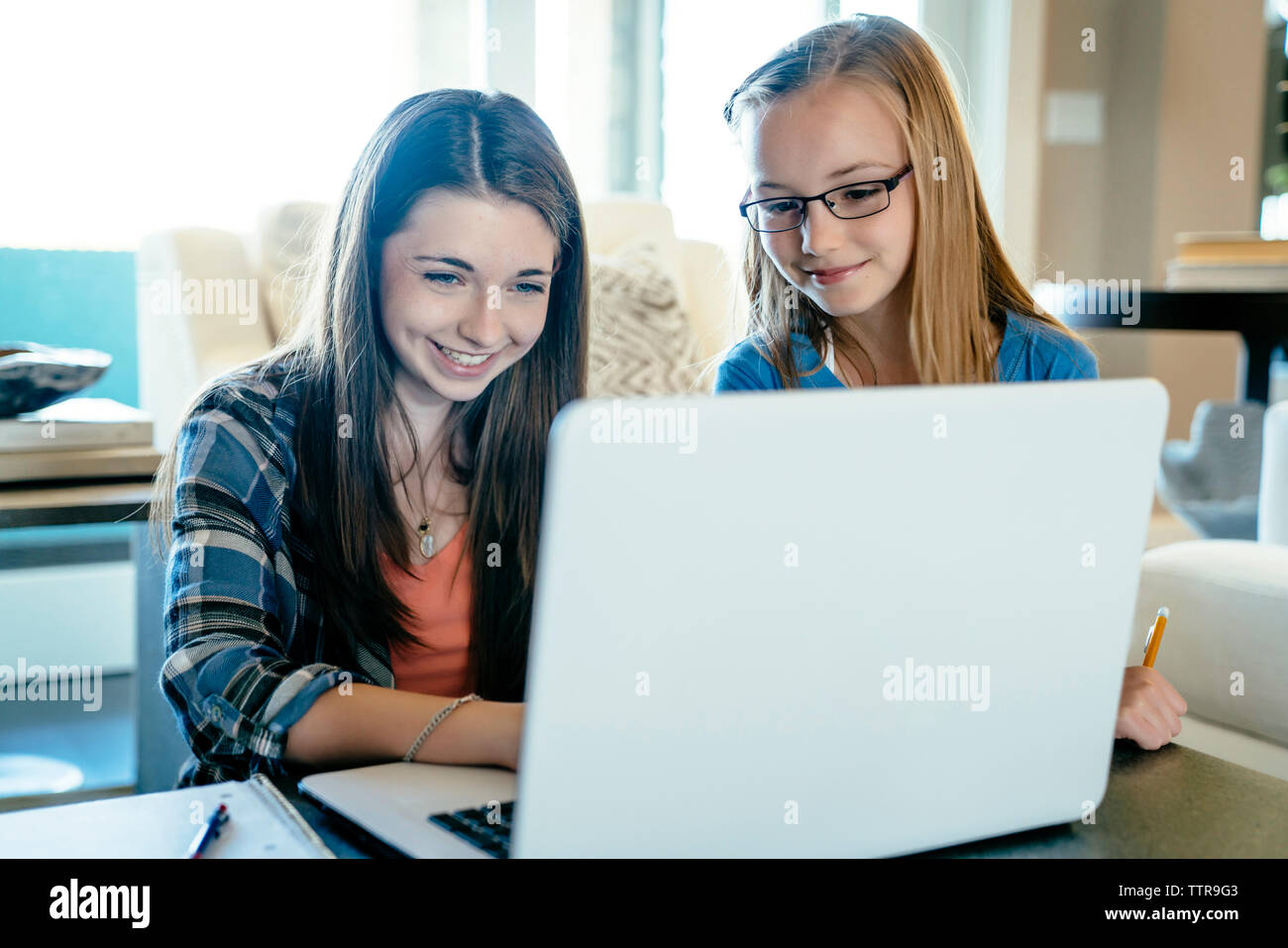 Sisters using laptop computer while doing homework at home Stock Photo ...