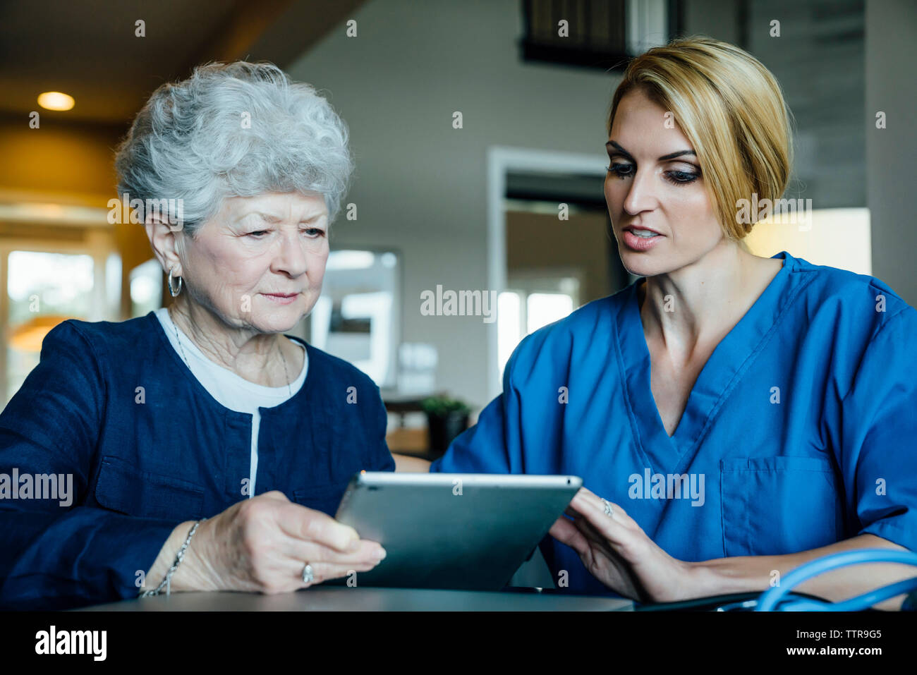 Home caregiver assisting senior woman in using tablet computer Stock ...