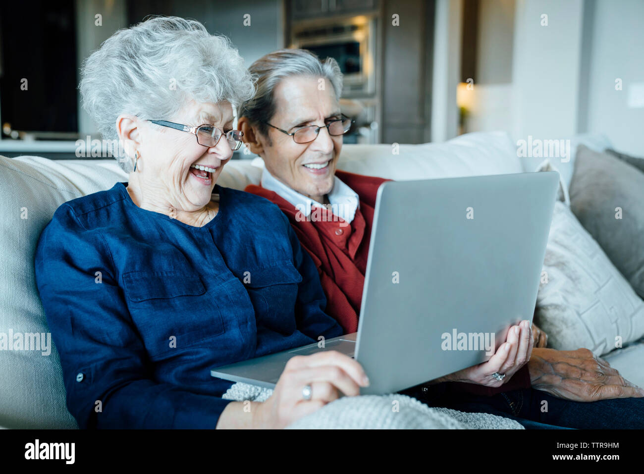 Happy senior couple video conferencing through laptop computer while ...