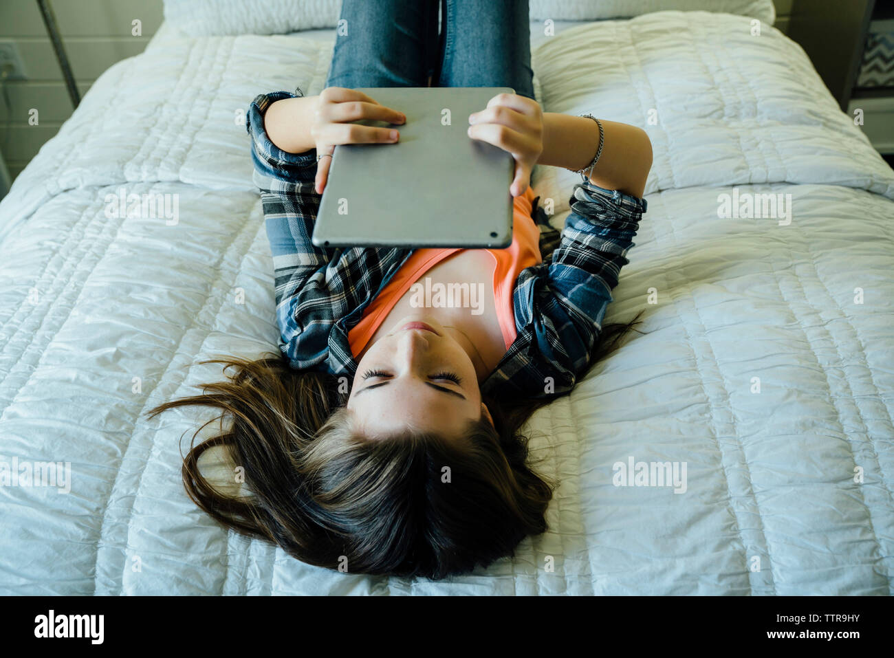 Teenage using tablet computer lying on bed hi-res stock photography and ...