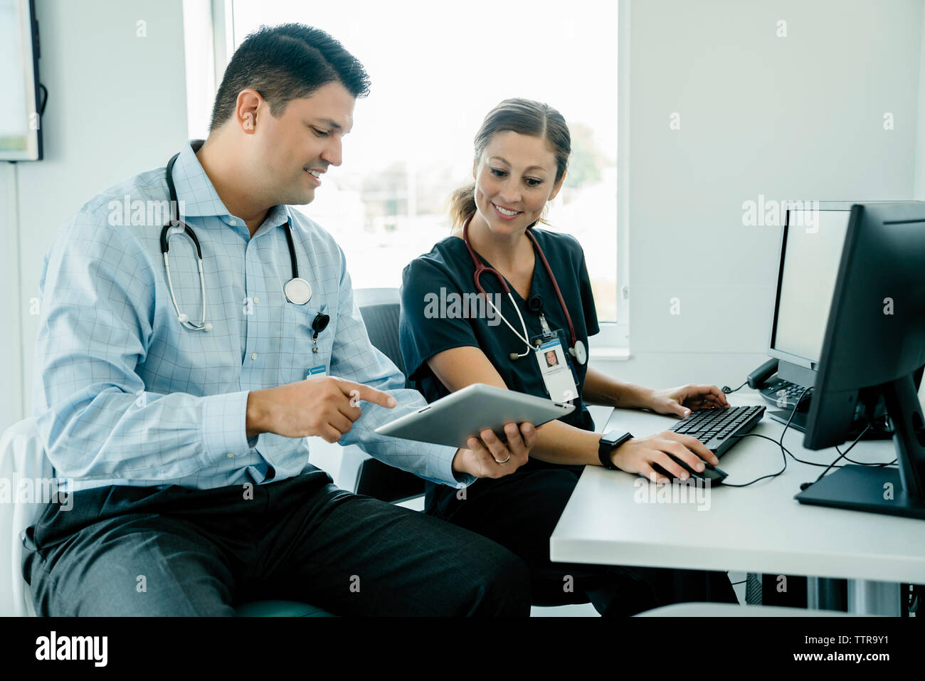 Doctor showing tablet computer to female colleague in hospital Stock ...