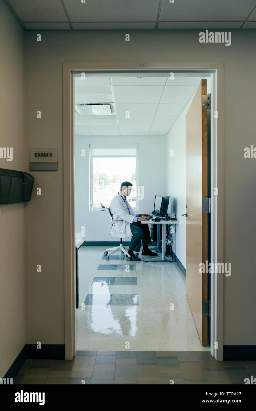 Side view of doctor using desktop computer while working in hospital ...