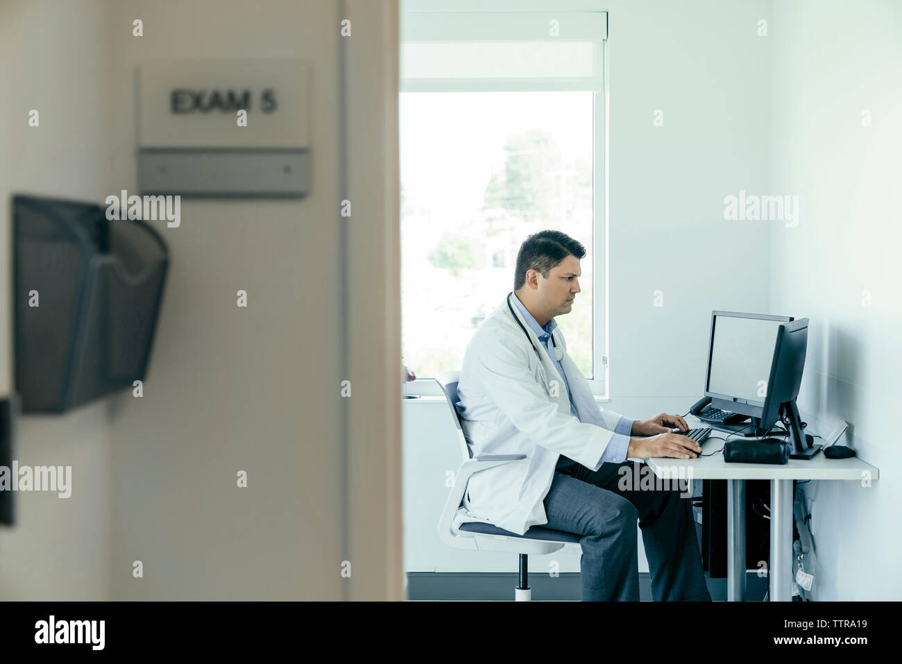 Side view of doctor using desktop computer while working in hospital ...