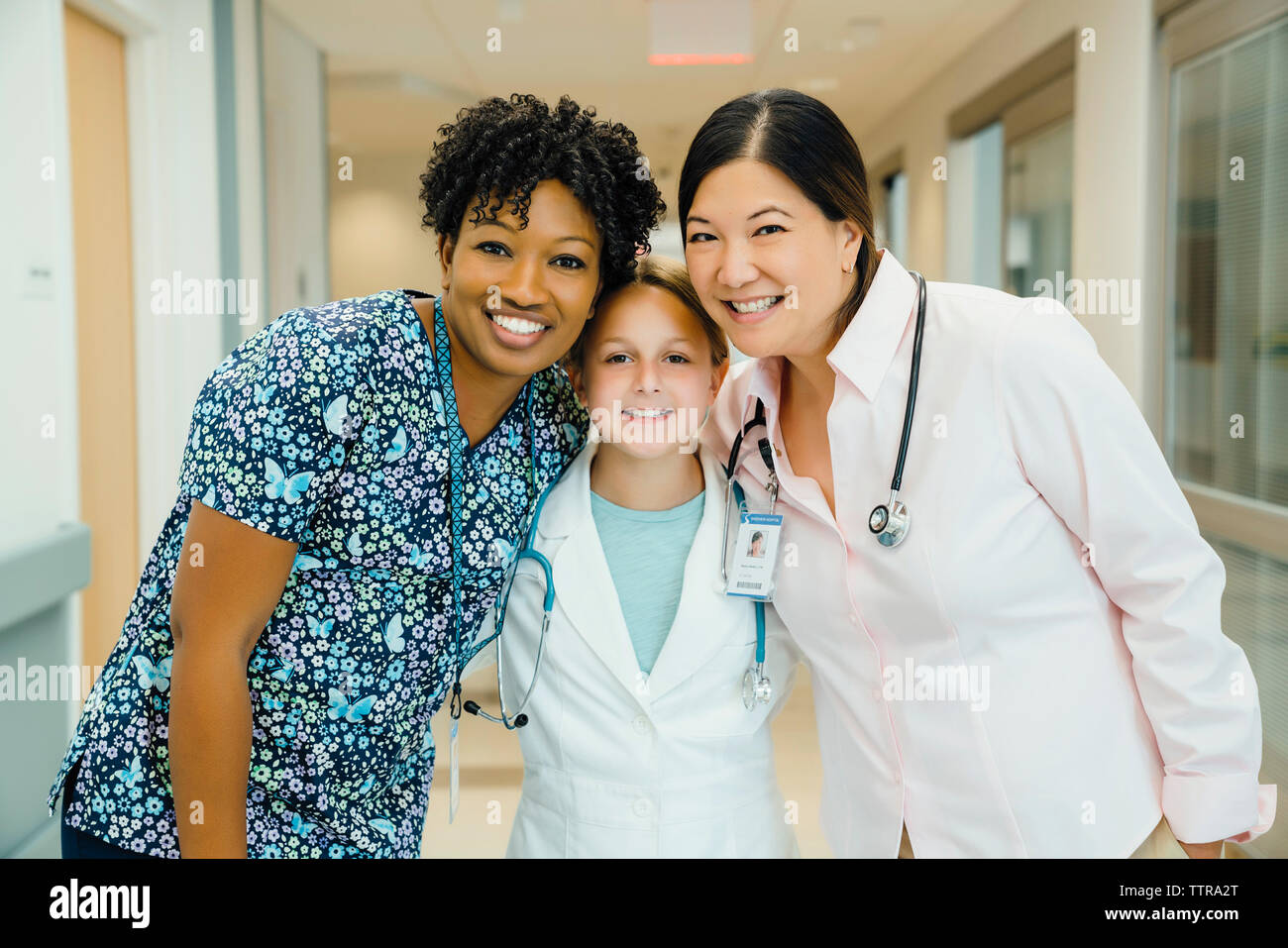 Portrait of confident female doctors with girl wearing lab coat in ...