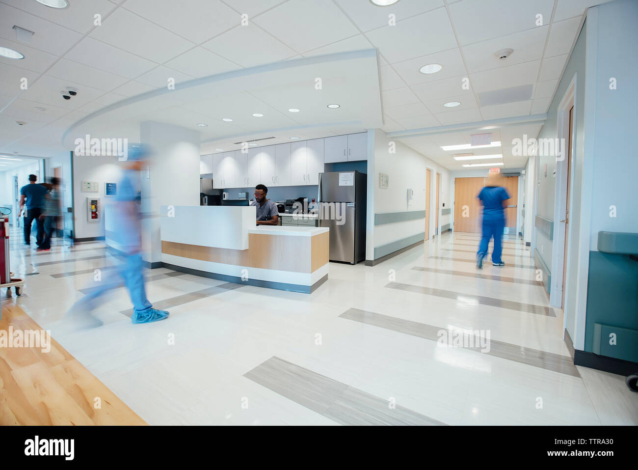 Doctor using desktop computer at reception while hospital staff working ...