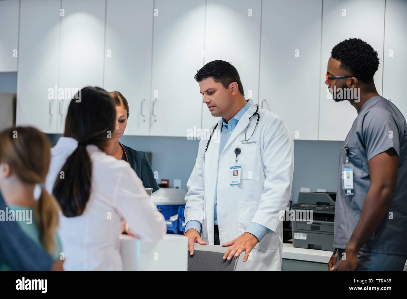 Doctors working at hospital reception with patient in foreground Stock ...