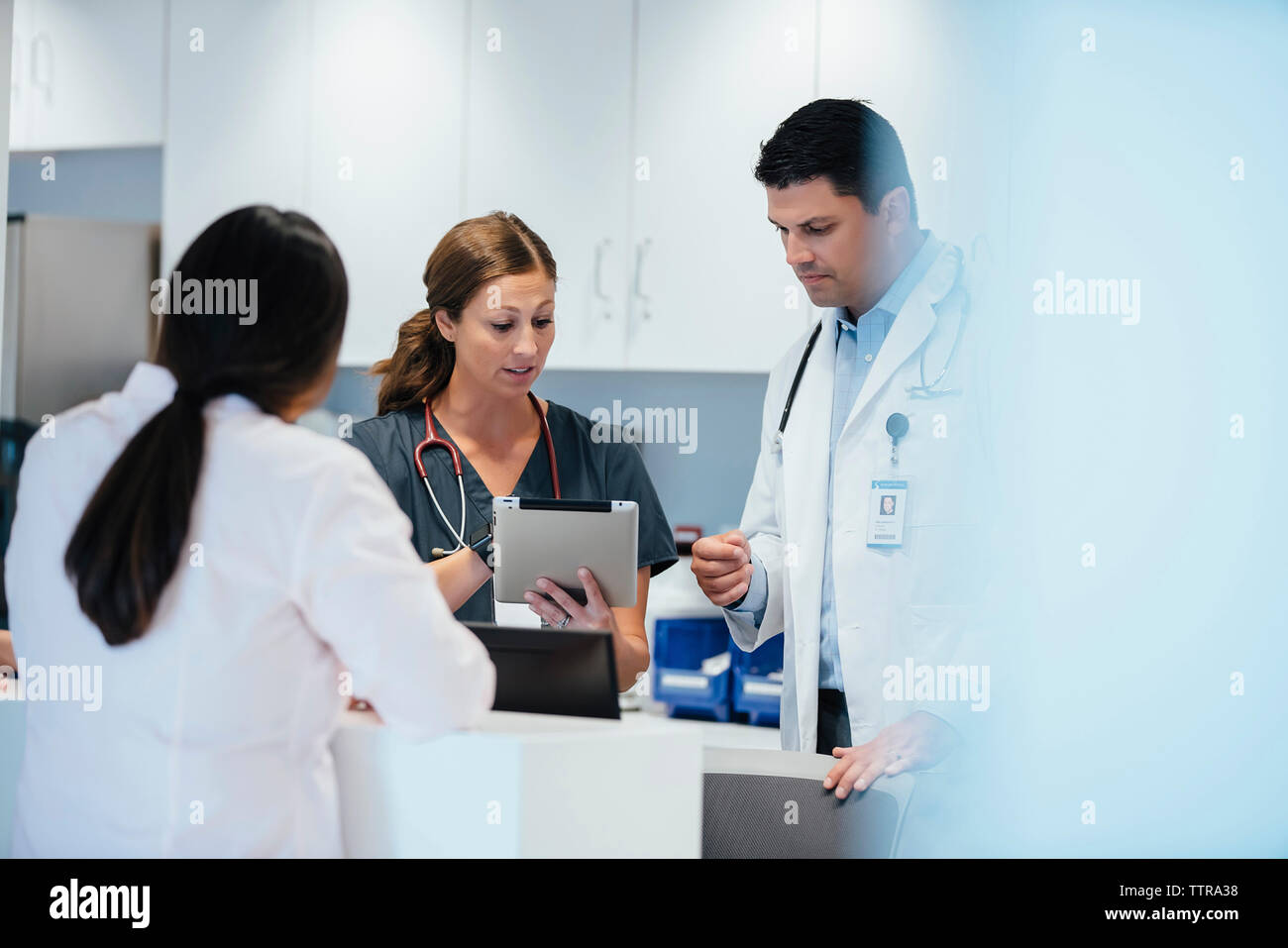 Nurse showing tablet computer to colleague with female doctor standing ...