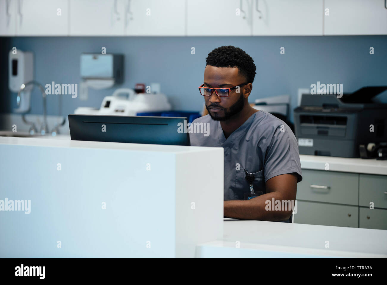 Confident doctor using desktop computer at hospital reception Stock ...