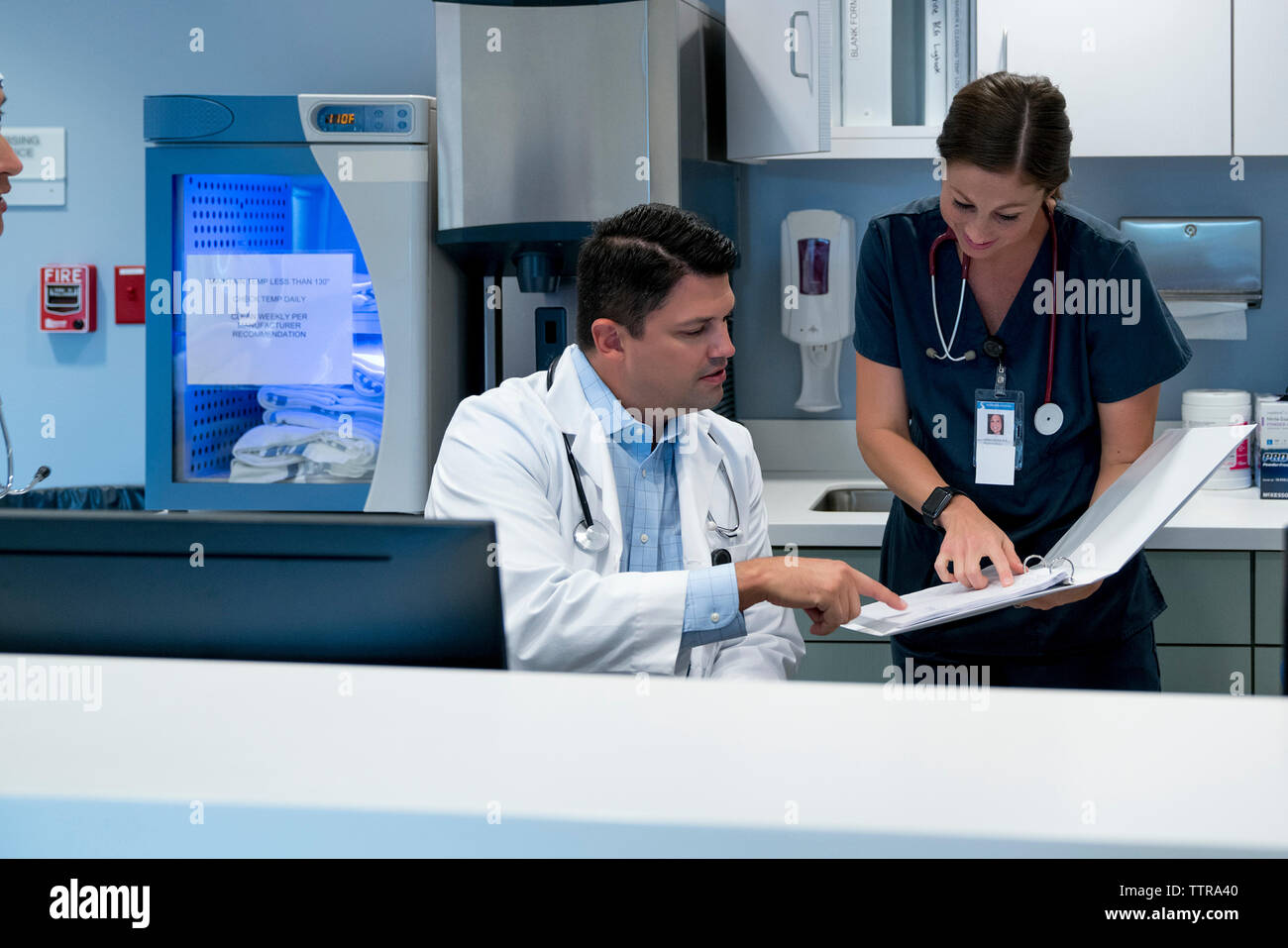 Doctor and nurse reviewing documents at hospital reception Stock Photo ...