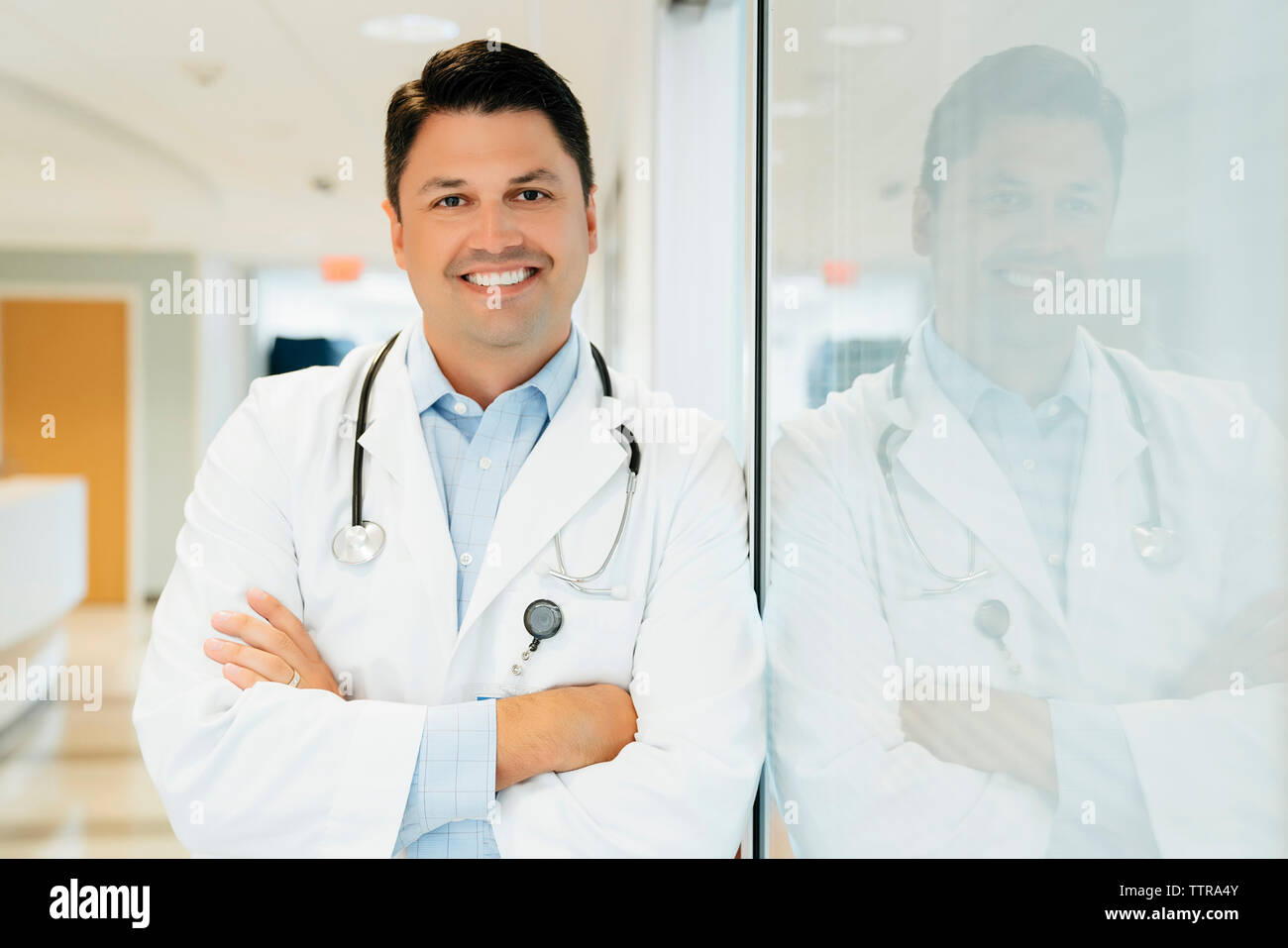Portrait of confident doctor with arms crossed standing in hospital ...