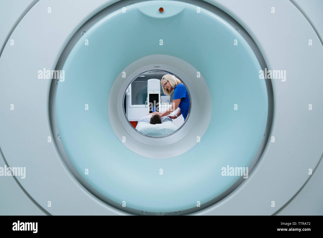 Nurse preparing patient for MRI Scan in hospital seen through scanner ...