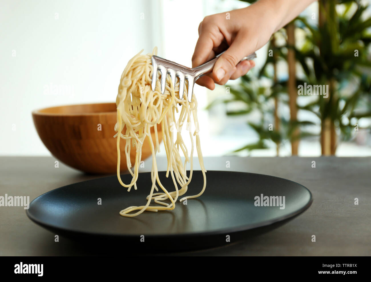 Female hand putting spaghetti onto plate Stock Photo - Alamy