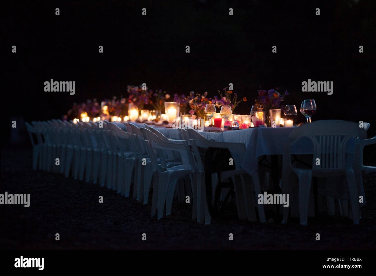 Lit candles on dining table at night Stock Photo - Alamy
