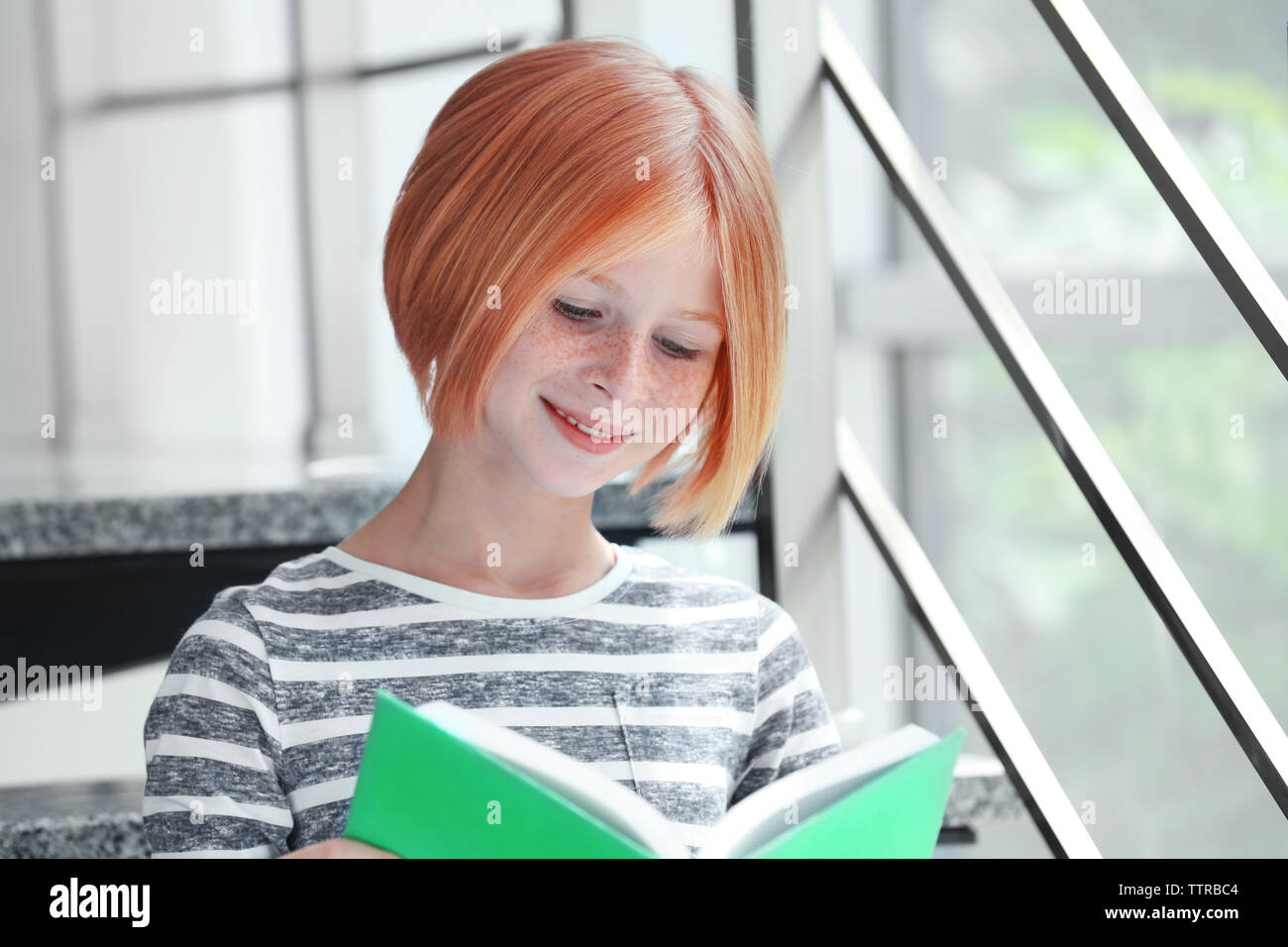 Cute girl reading book on light background Stock Photo - Alamy