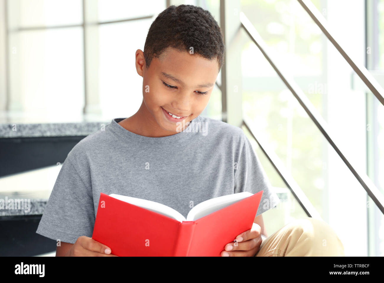 Cute boy reading book on light background Stock Photo - Alamy