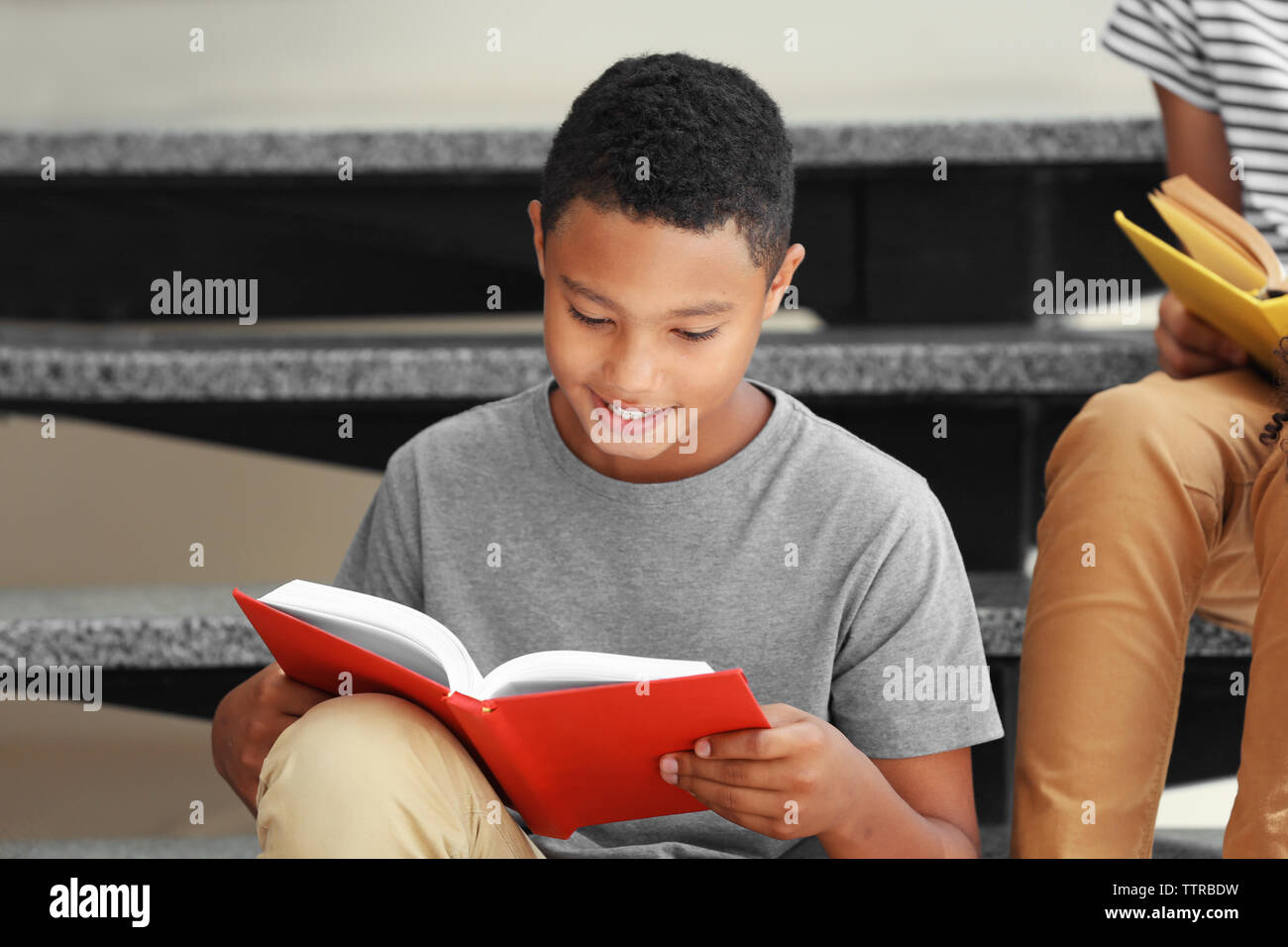 Cute boy reading book on light background Stock Photo - Alamy