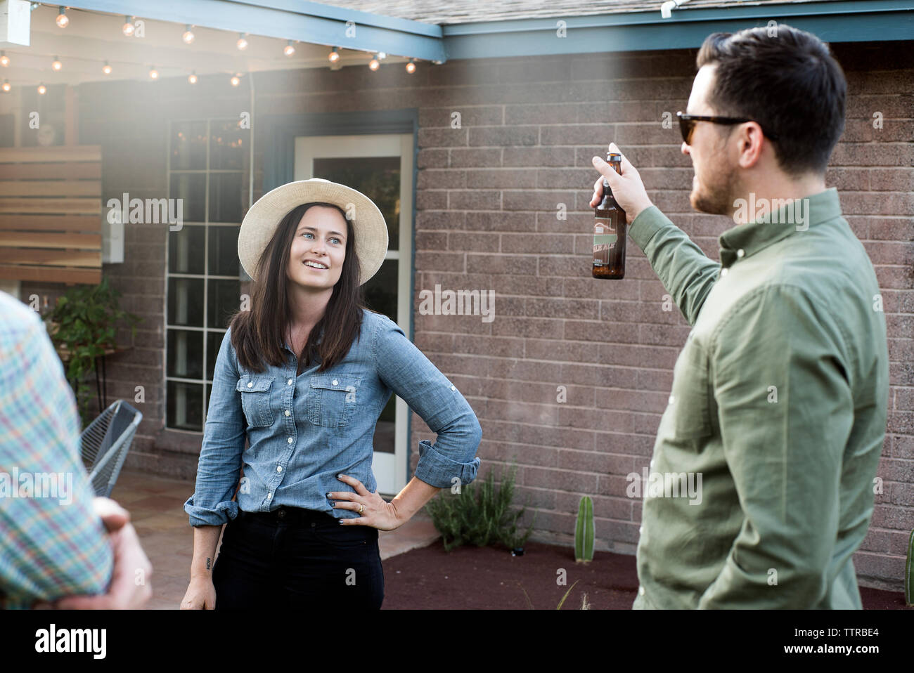 Couple talking while standing with friend in backyard Stock Photo - Alamy
