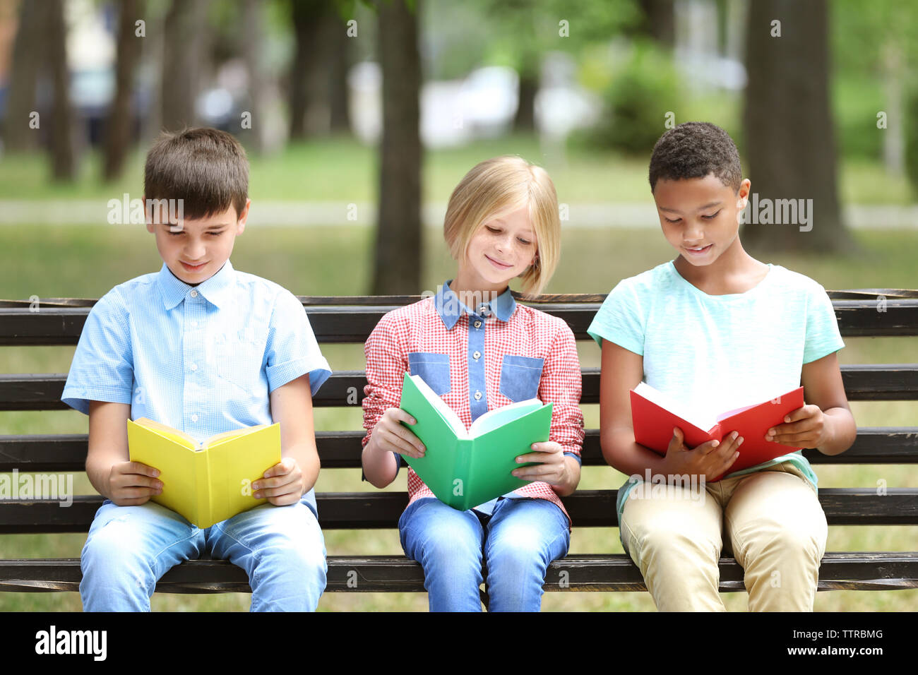 Cute kids reading books on bench Stock Photo - Alamy