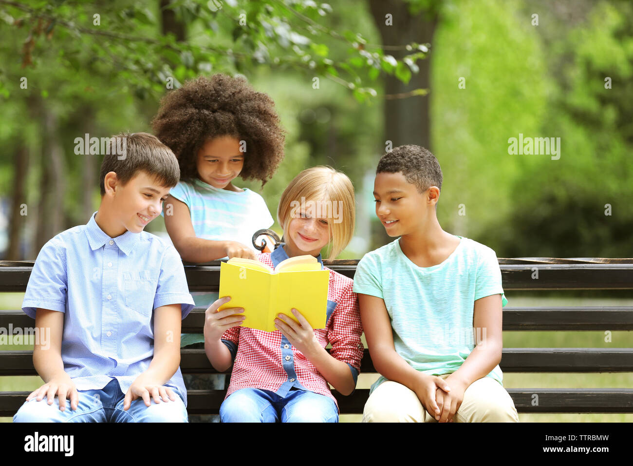 Cute kids reading book on bench Stock Photo - Alamy