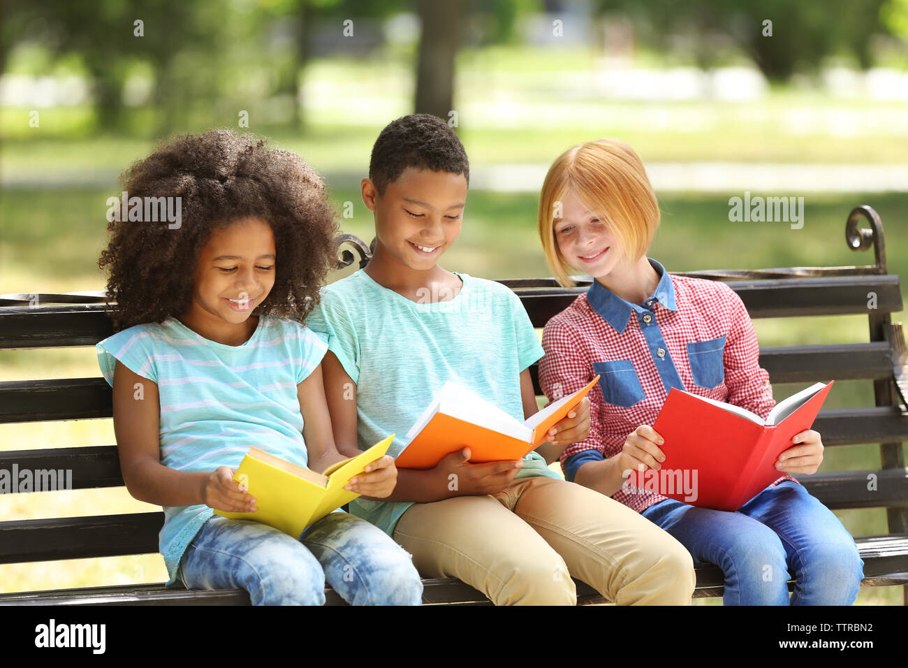 Cute kids reading books on bench Stock Photo - Alamy