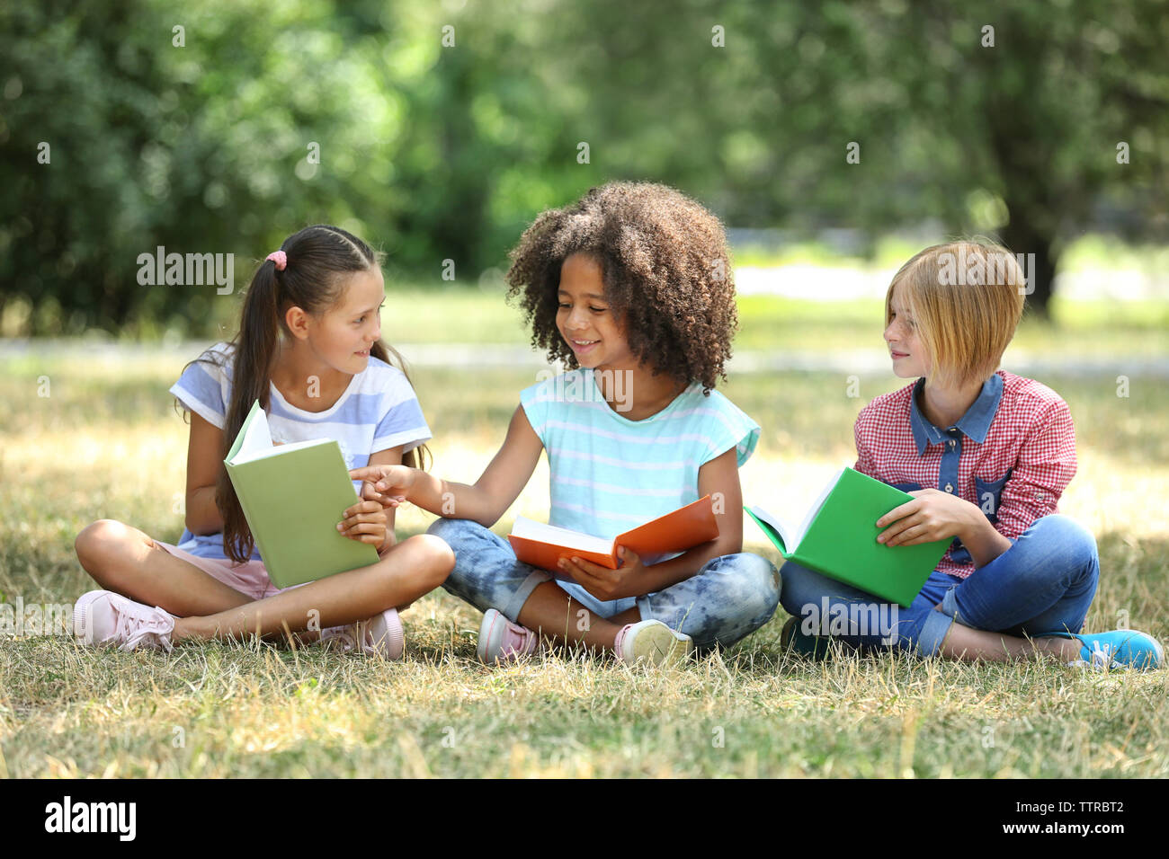 Cute kids reading books on green grass Stock Photo - Alamy